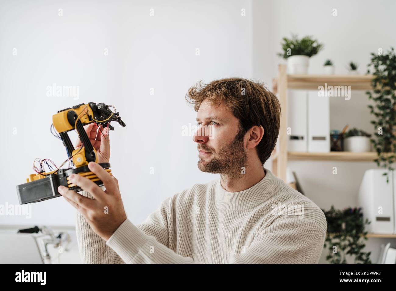 Engineer analyzing robotic arm in office Stock Photo - Alamy
