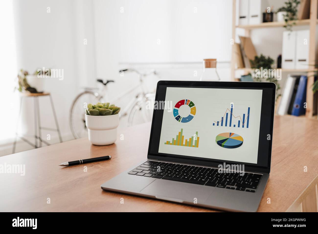 Graphs and chart on laptop screen at desk in office Stock Photo - Alamy