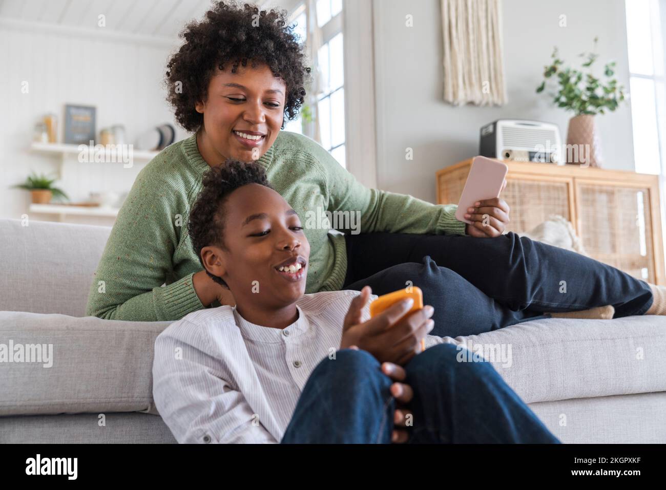 Happy boy sharing mobile phone with mother at home Stock Photo - Alamy