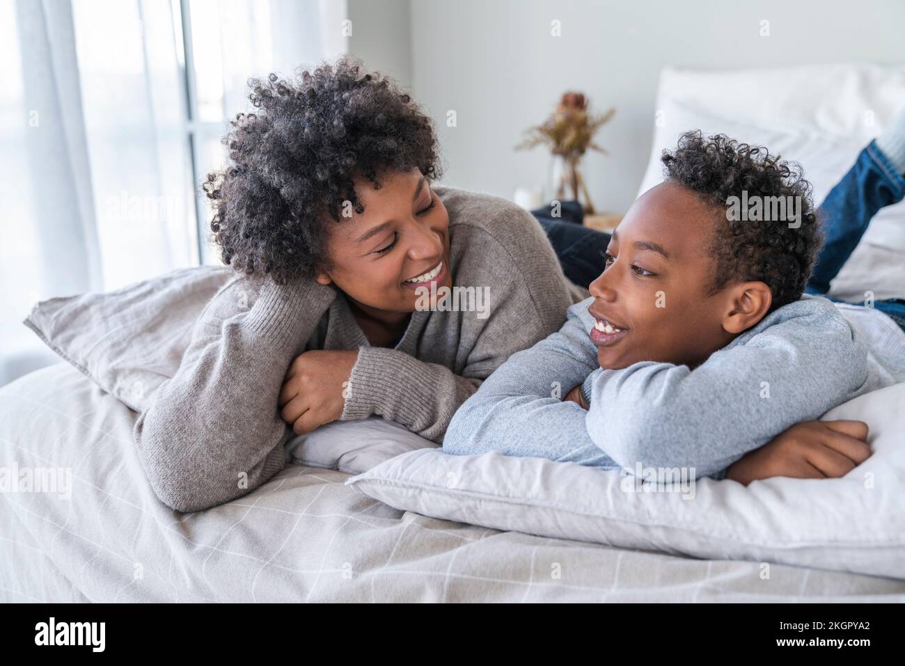 Happy mother and son having conversation lying on bed at home Stock ...
