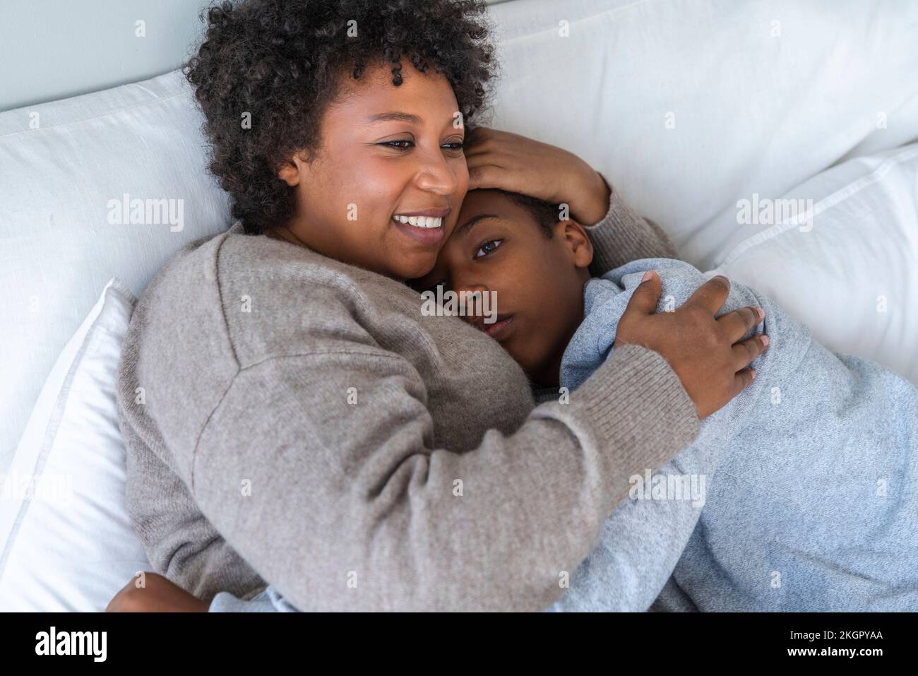 Happy mother cuddling son in bed at home Stock Photo - Alamy