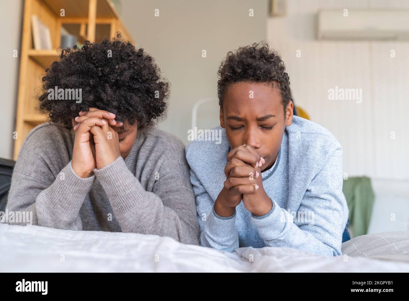 Mother and son with eyes closed praying by bed at home Stock Photo - Alamy