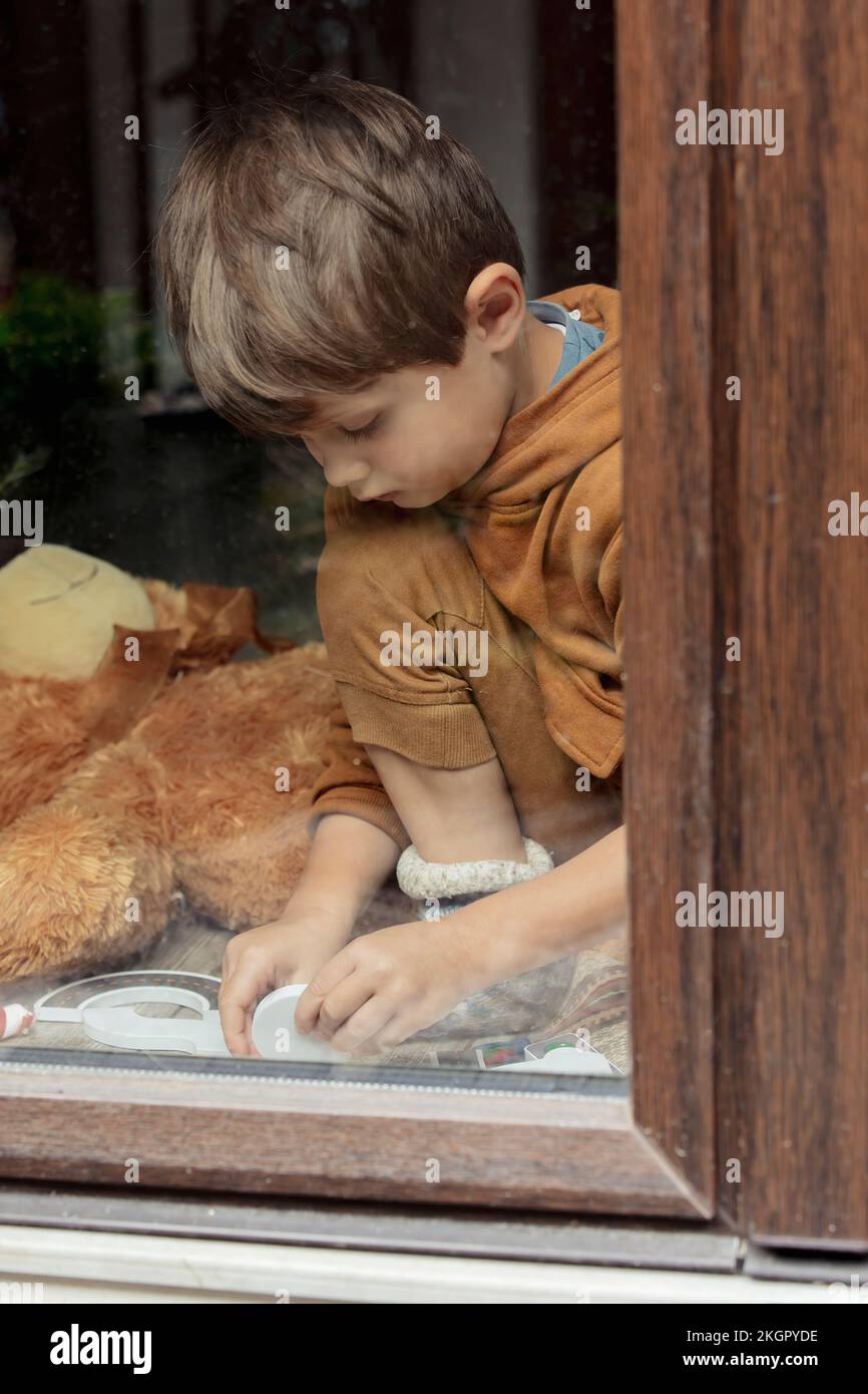 Boy sitting in home seen through glass window Stock Photo - Alamy