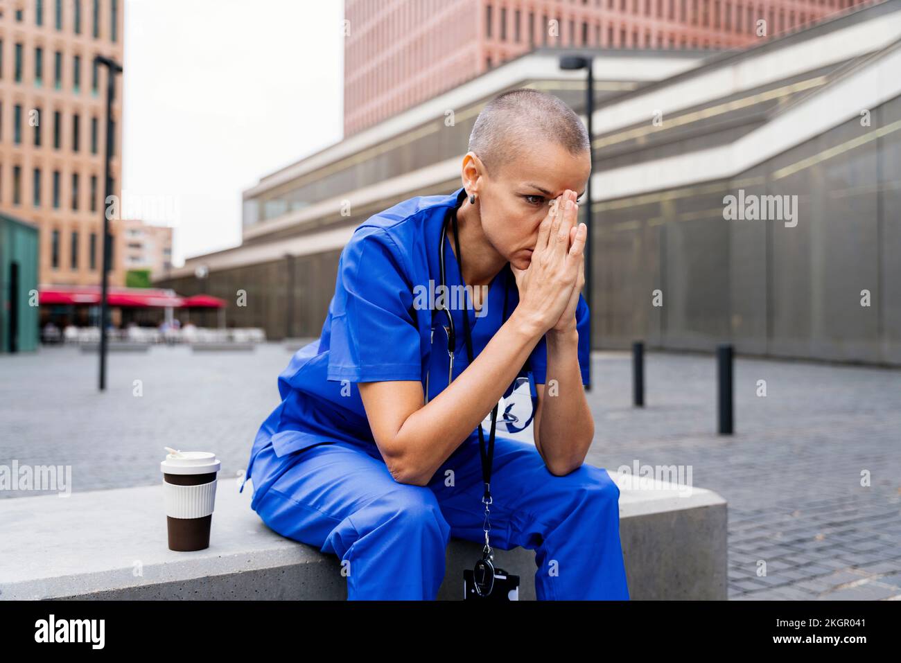 Worried female nurse contemplating on bench Stock Photo - Alamy