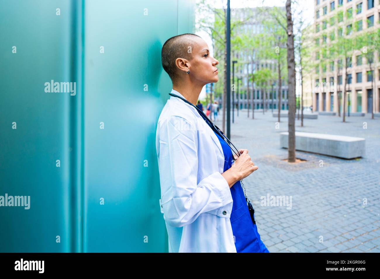 Thoughtful female doctor leaning on wall Stock Photo - Alamy