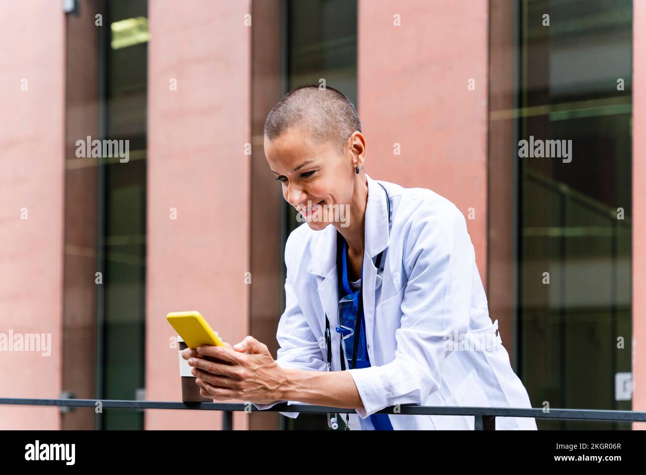 Smiling mature doctor using mobile phone outside hospital Stock Photo ...