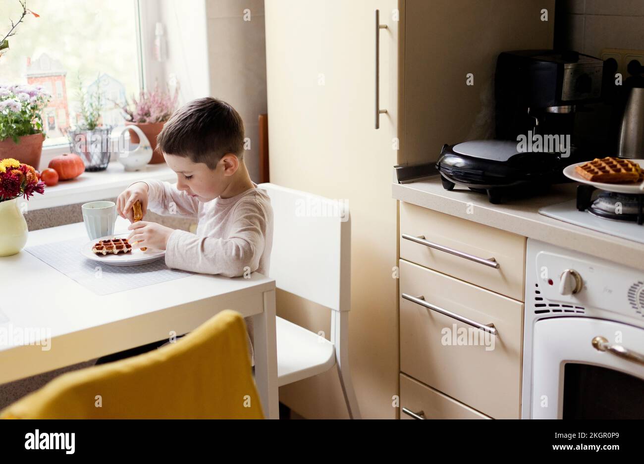 Boy having breakfast on dining table in kitchen Stock Photo - Alamy