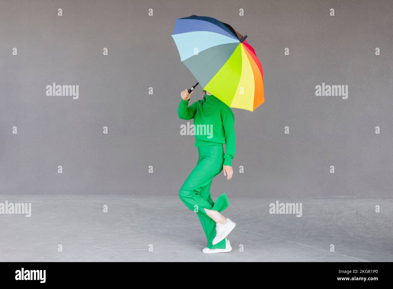Woman covering face with multi colored umbrella in front of wall Stock ...