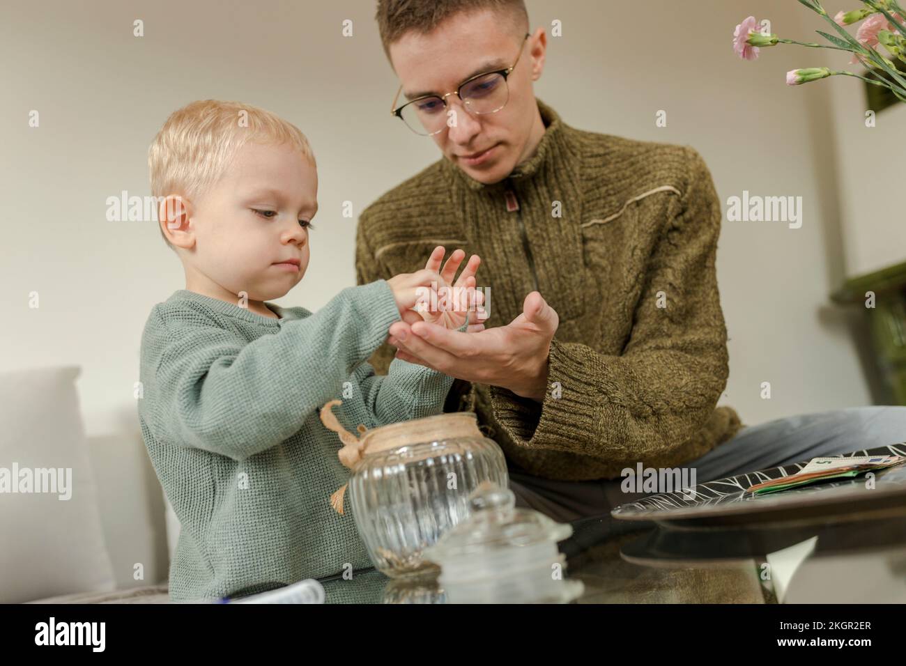 Young man with son counting coins at home Stock Photo - Alamy