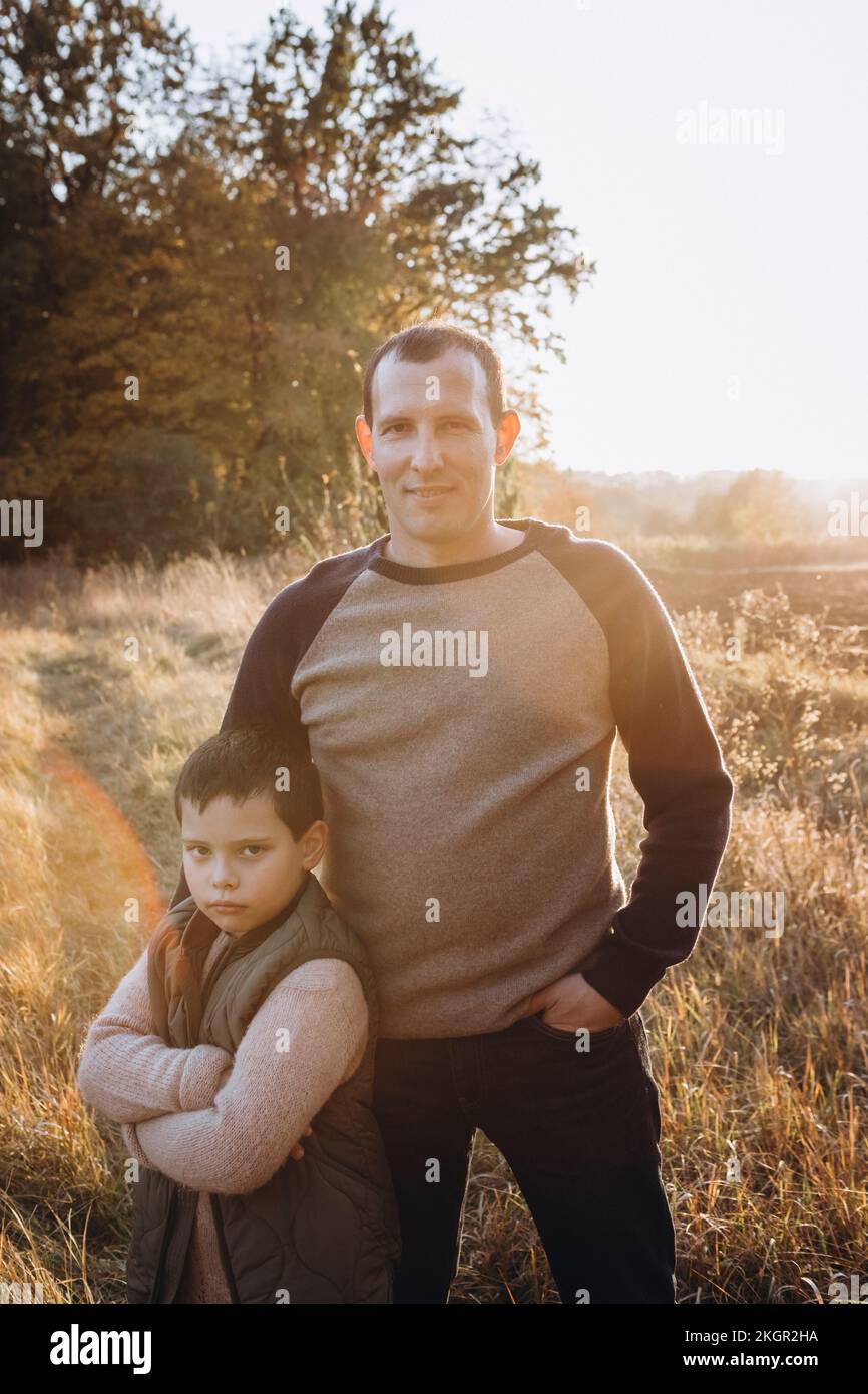 Smiling father with son standing at field on sunny day Stock Photo - Alamy