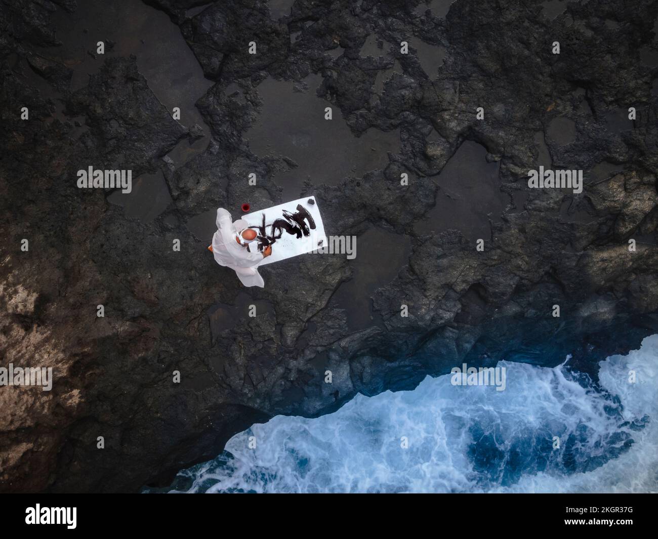 Monk doing calligraphy sitting on rock by sea Stock Photo - Alamy