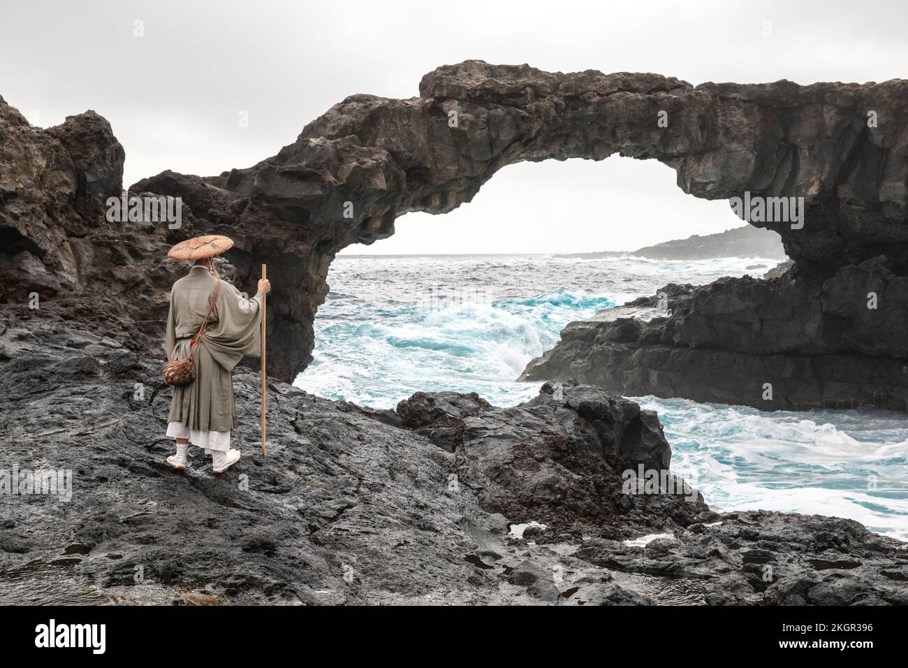Monk wearing hat standing in front of rock arch Stock Photo - Alamy