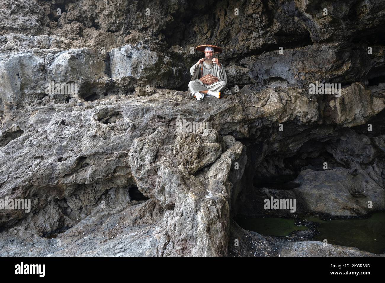 Monk practicing meditation on rock Stock Photo - Alamy
