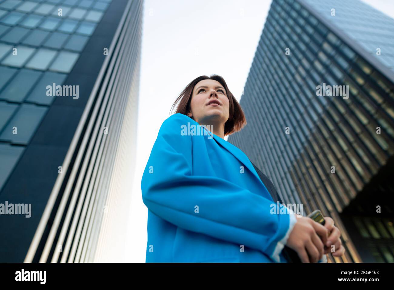 Businesswoman wearing blue blazer standing near office building Stock ...