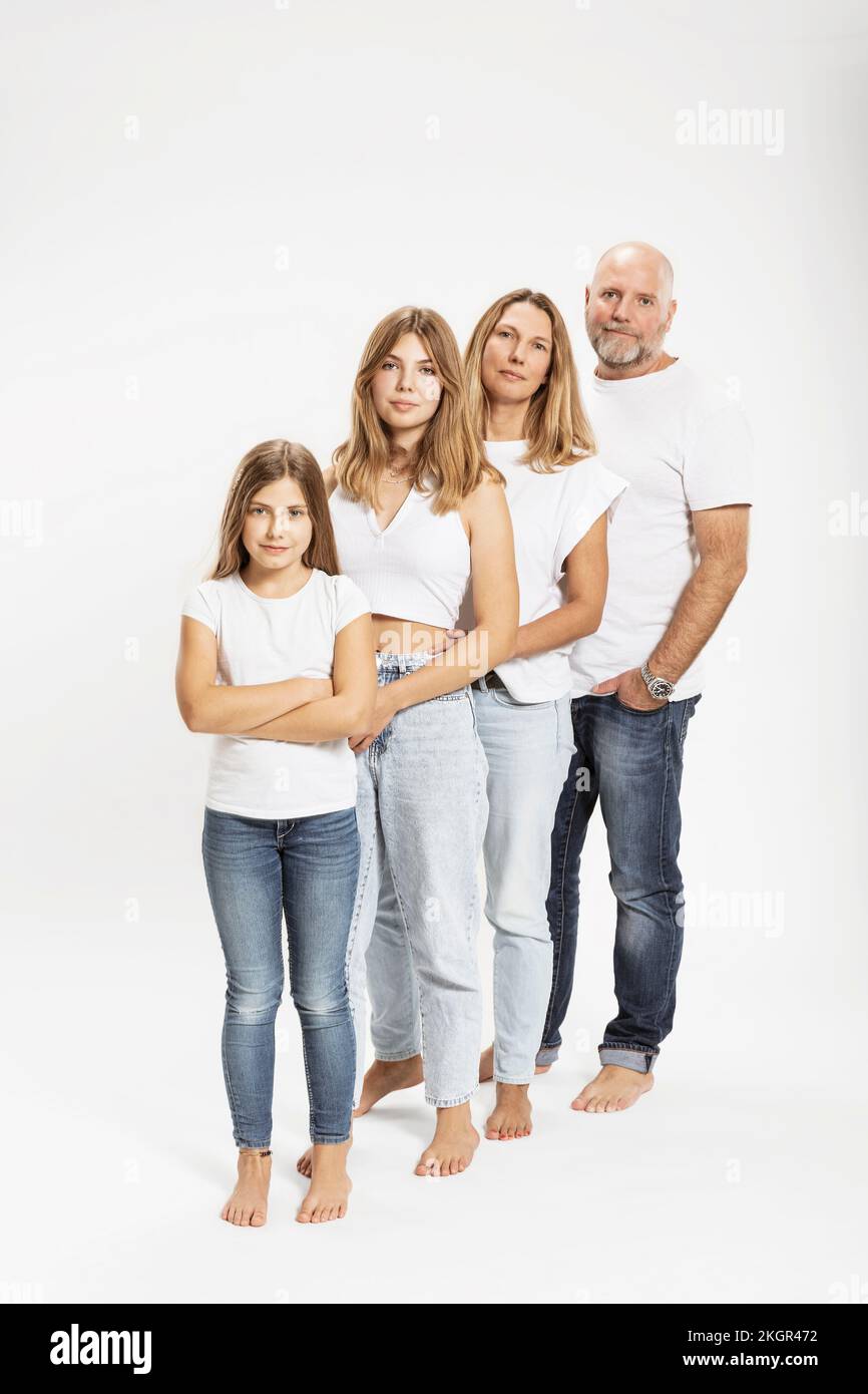 Confident family with two children standing in row at studio Stock ...