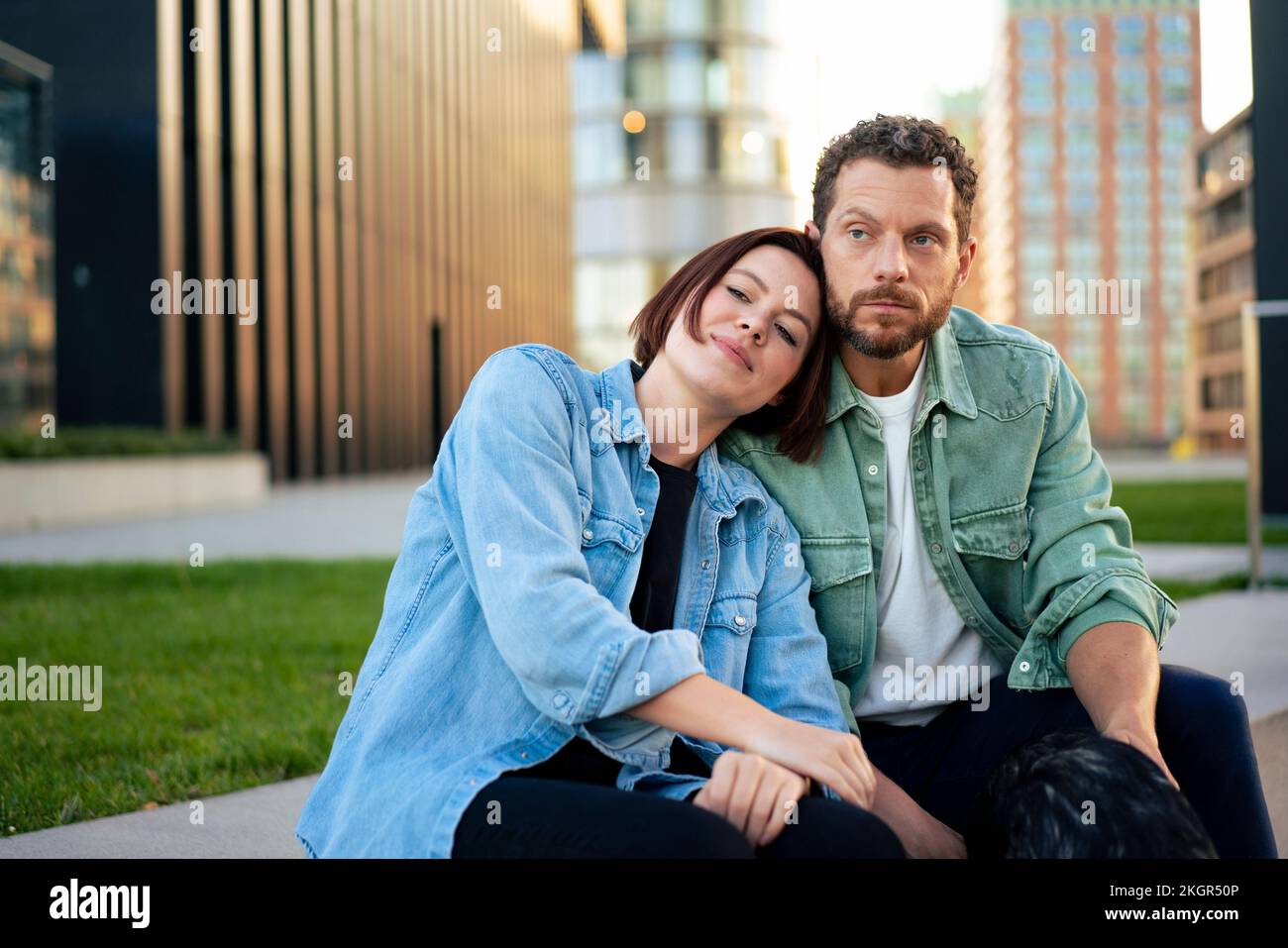 Couple wearing denim shirts sitting on bench Stock Photo - Alamy