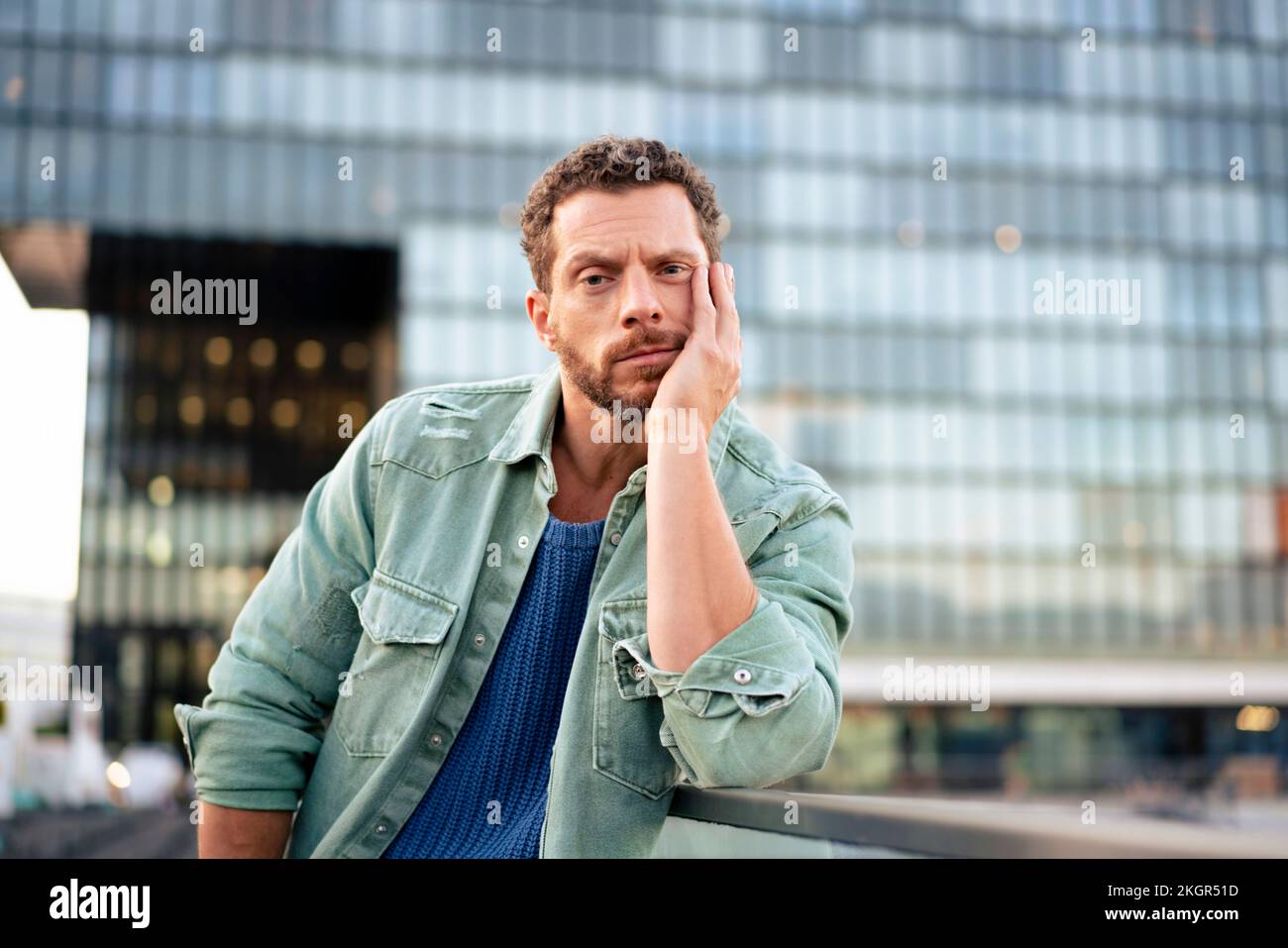 Man wearing denim shirt leaning on elbow at railing Stock Photo - Alamy