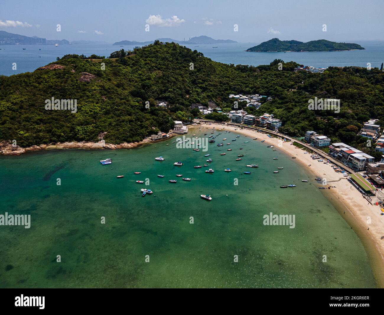 A bird's eye view of Peng Chau beach surrounded by green forested hills ...