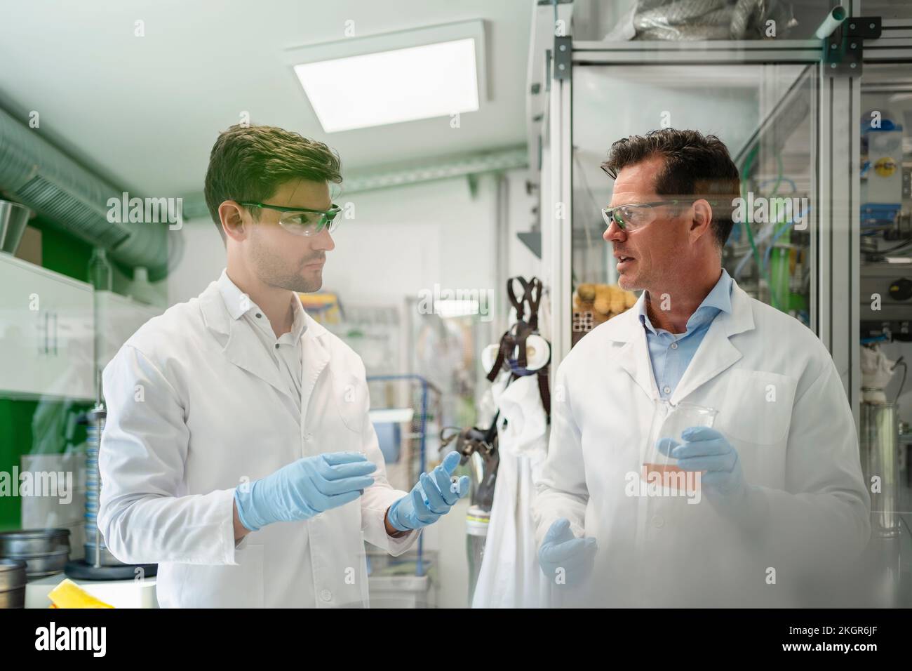 Scientists discussing with colleague and doing thermolysis experiment ...
