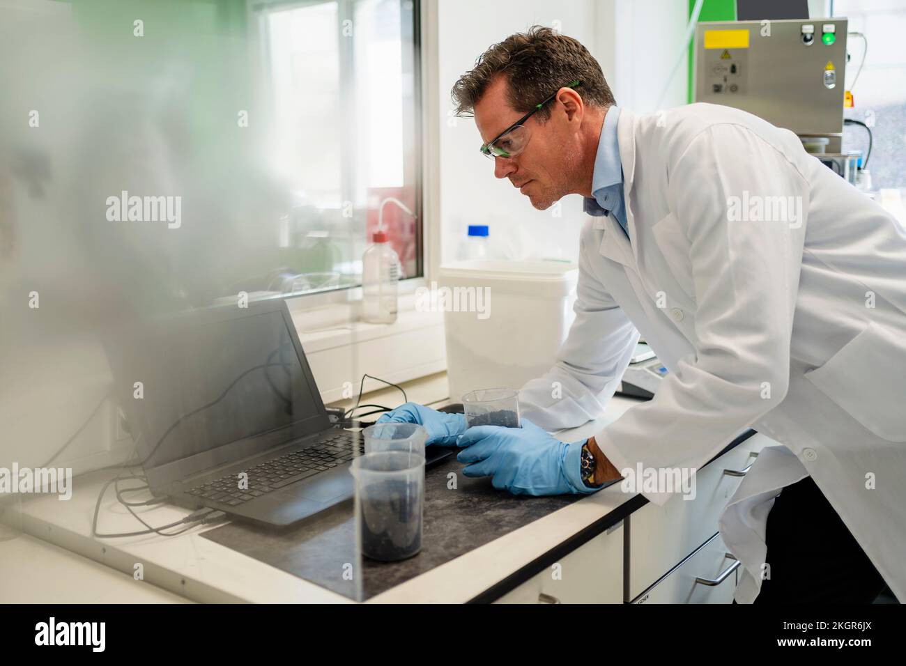 Scientist wearing lab coat using laptop in laboratory Stock Photo - Alamy