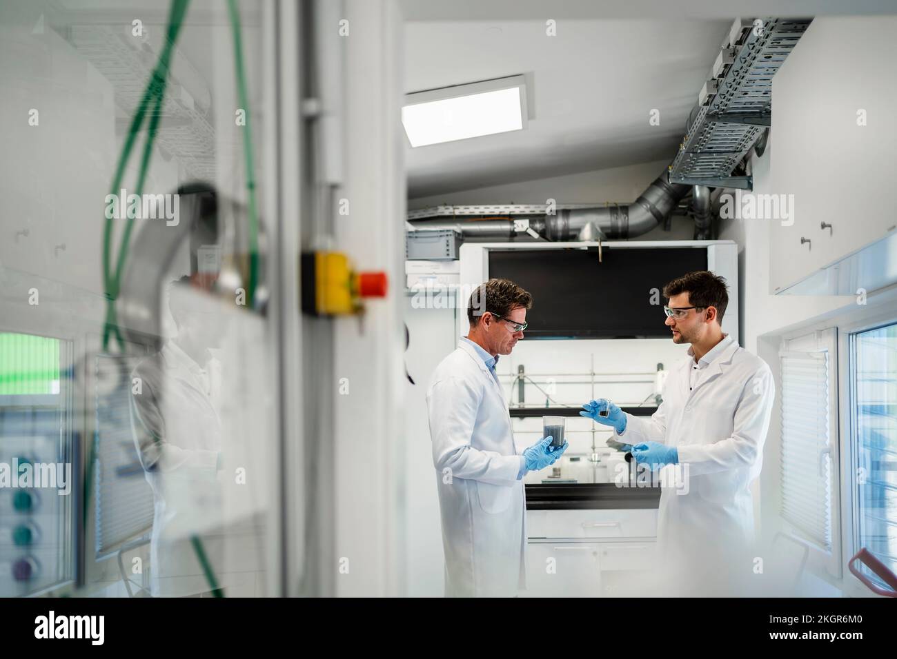 Mature scientist with colleague discussing over thermolysis experiment ...
