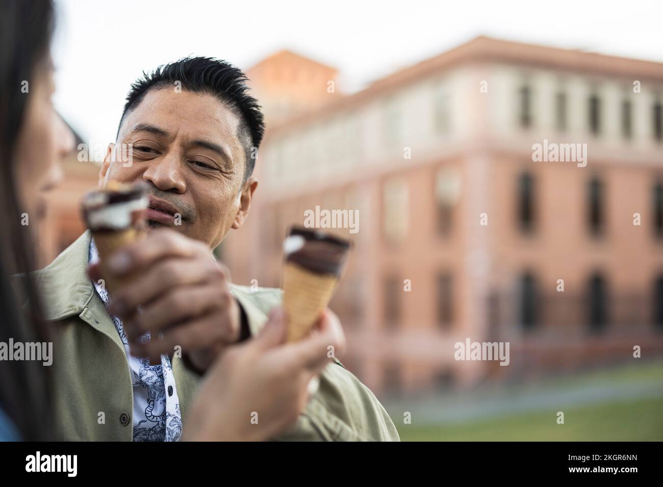 Smiling mature man feeding ice cream cone to woman Stock Photo - Alamy