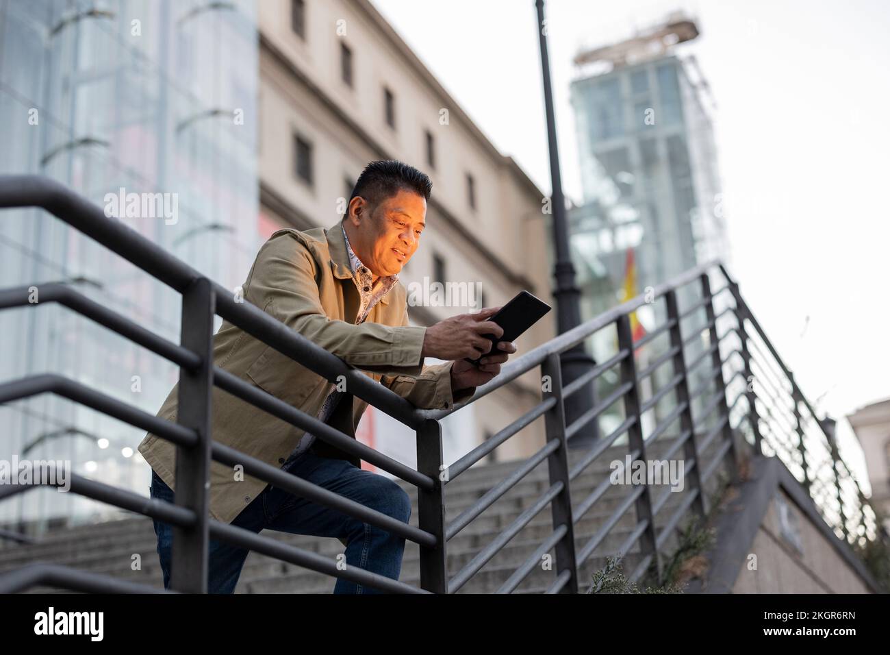 Mature man using tablet PC leaning on railing Stock Photo - Alamy