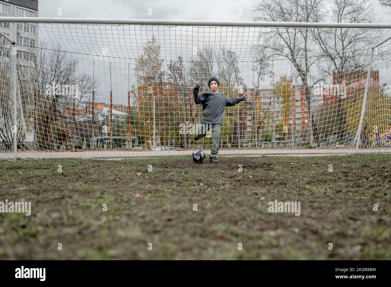Boy kicking ball in front of goal post at sports field Stock Photo - Alamy