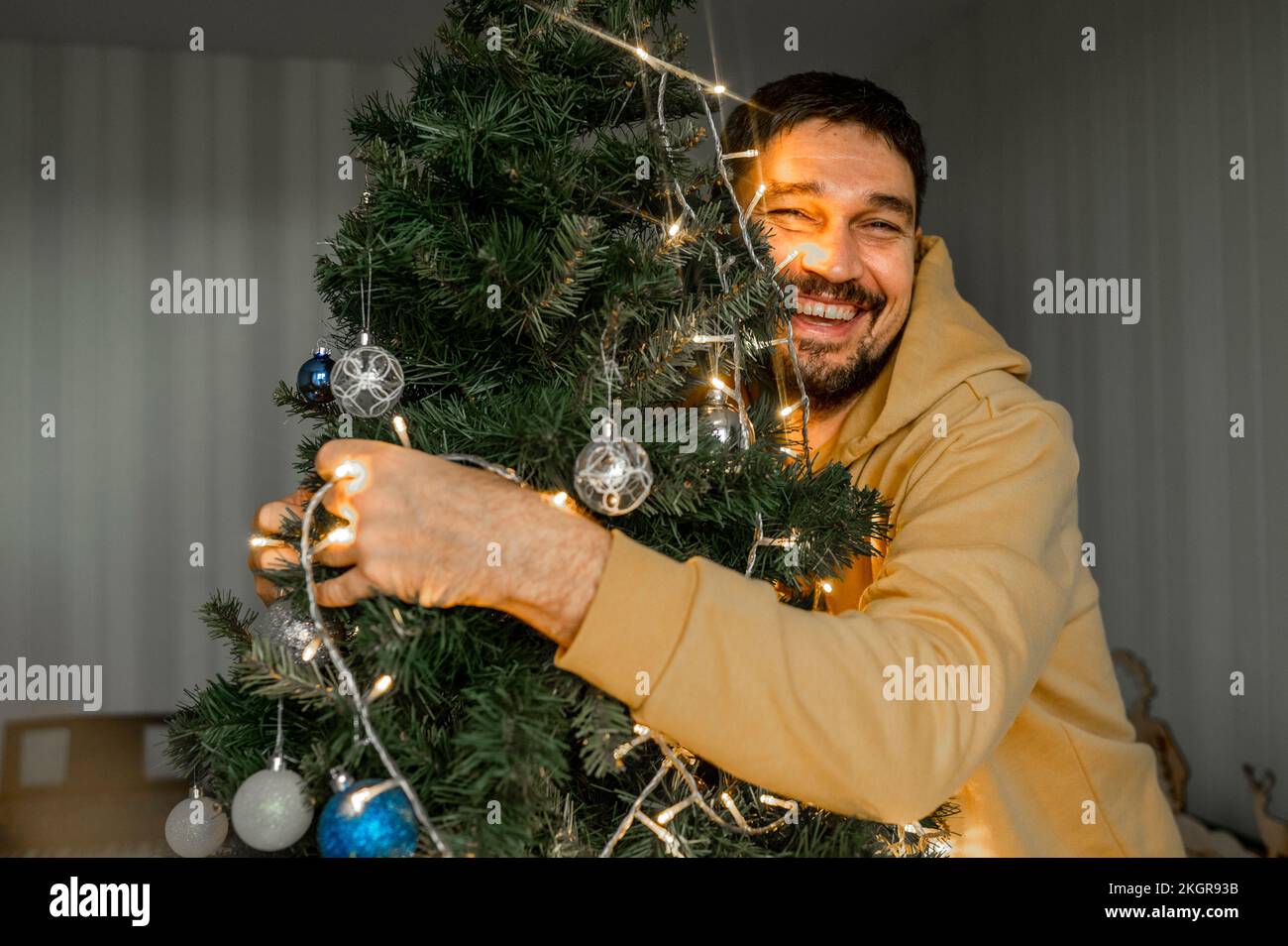 Happy man hugging illuminated Christmas tree at home Stock Photo - Alamy