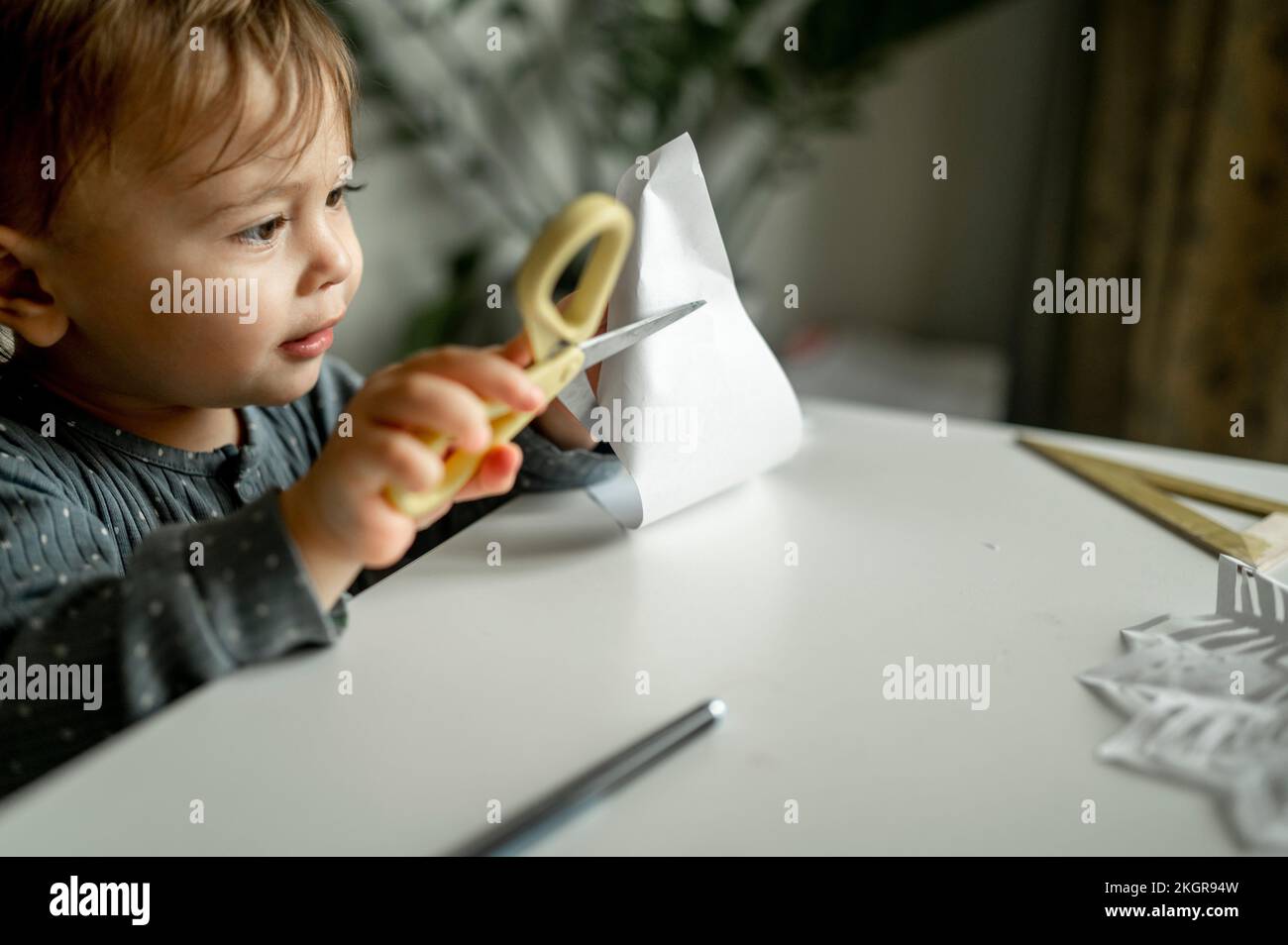 Boy cutting paper with scissor at table in home Stock Photo - Alamy