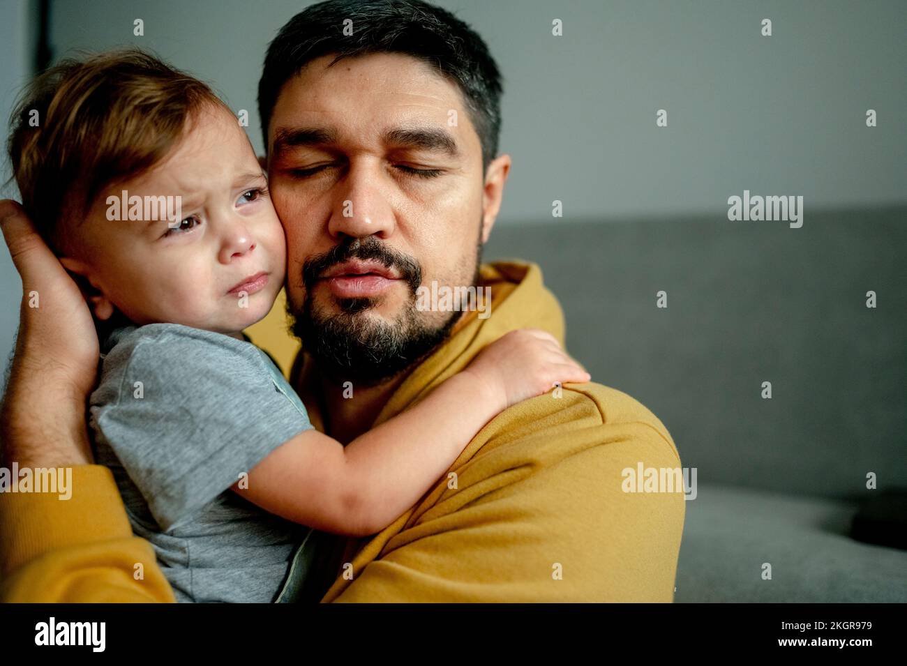 Father hugging crying son in living room at home Stock Photo - Alamy