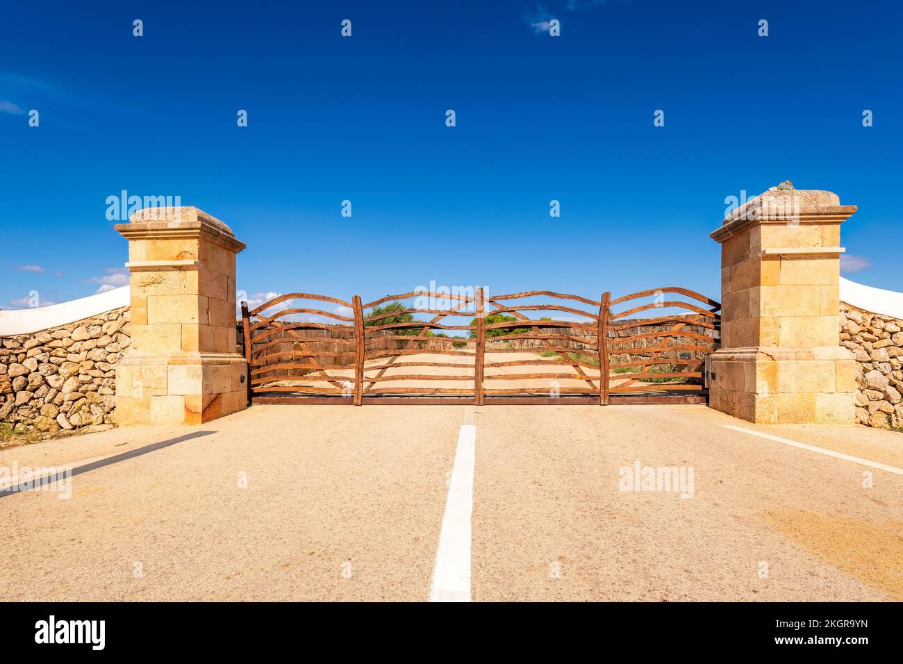 Spain, Balearic Islands, Menorca, Wooden gate in middle of asphalt road ...