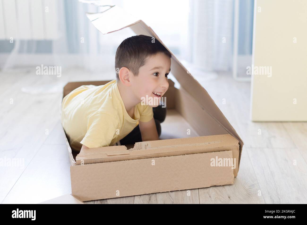 Cute playful boy hiding in cardboard box at home Stock Photo - Alamy