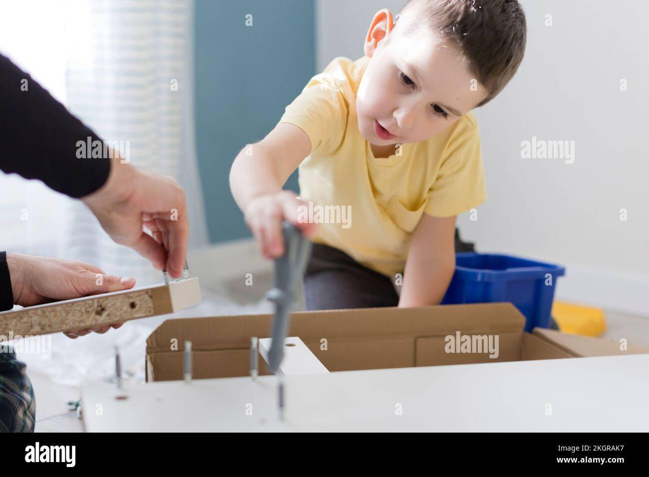 Boy helping father assembling table at home Stock Photo - Alamy