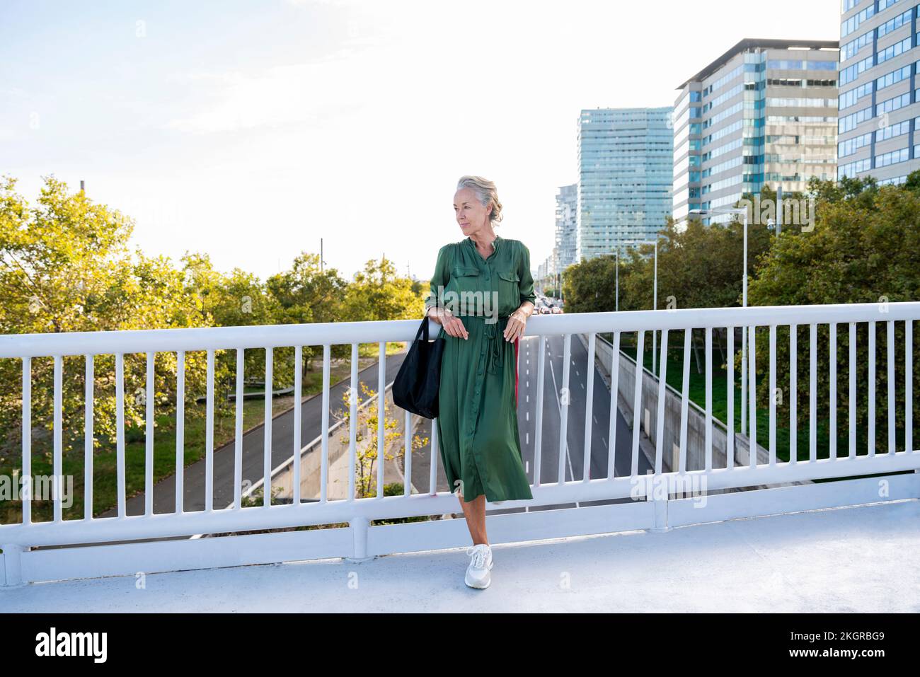 Mature woman leaning on railing in city Stock Photo - Alamy