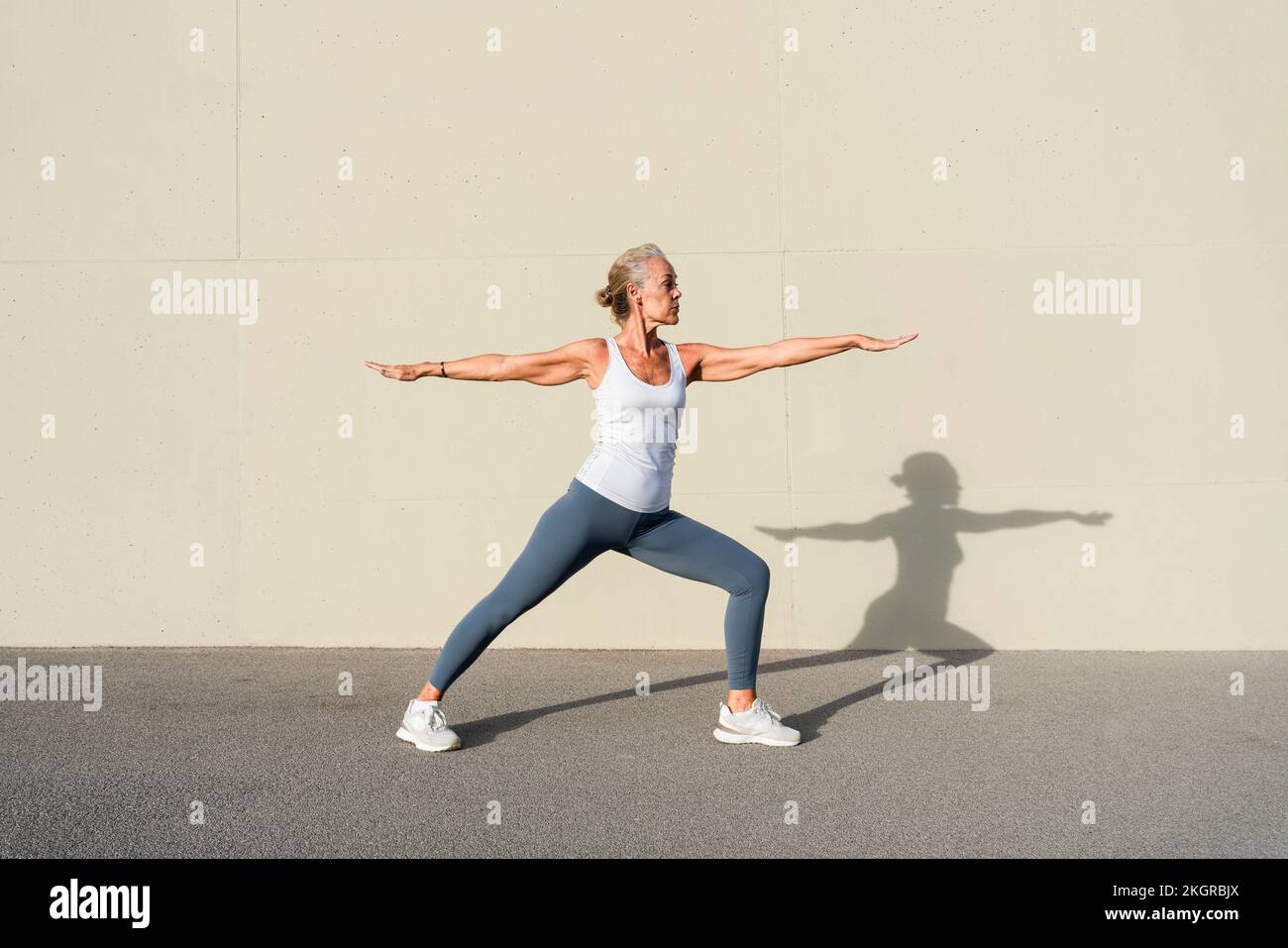 Woman doing Warrior 2 Pose in front of wall Stock Photo - Alamy