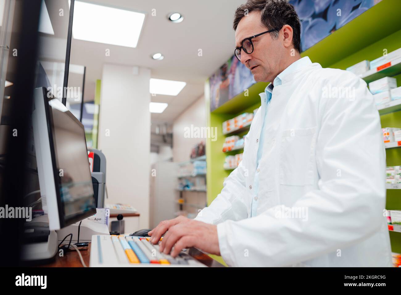 Pharmacist using desktop PC in store Stock Photo - Alamy