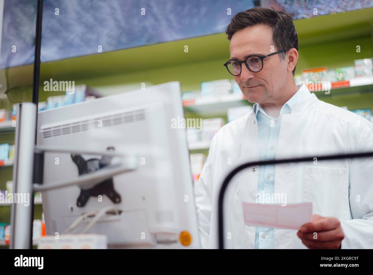 Pharmacist holding prescription searching medicine in database through ...