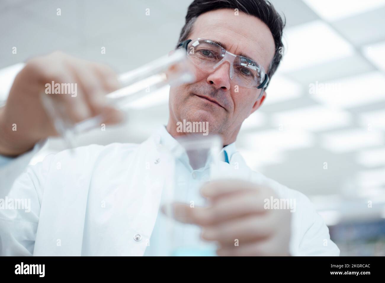 Chemist pouring chemical from test tube to flask in laboratory Stock ...