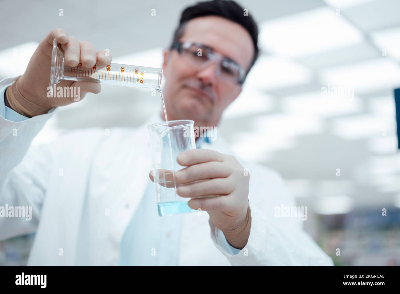 Chemist pouring solution from test tube to flask in laboratory Stock ...