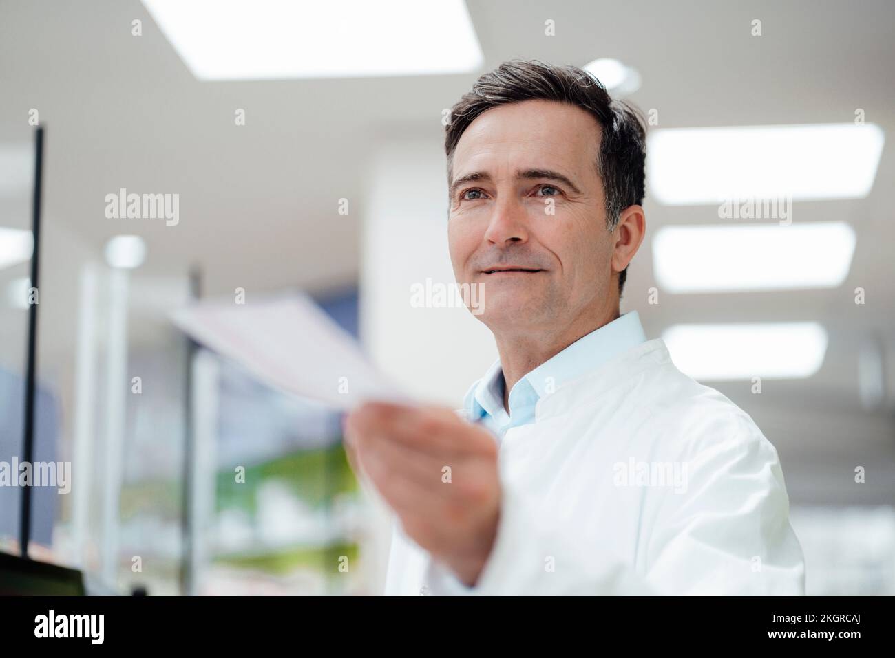 Smiling pharmacist holding prescription in pharmacy Stock Photo - Alamy