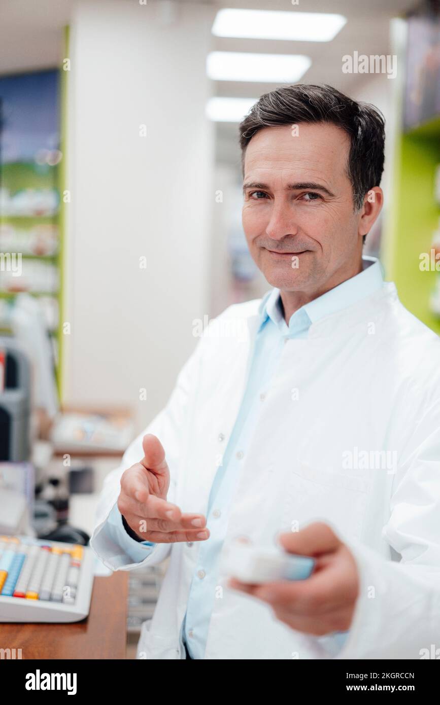 Smiling pharmacist showing medicine at store Stock Photo - Alamy