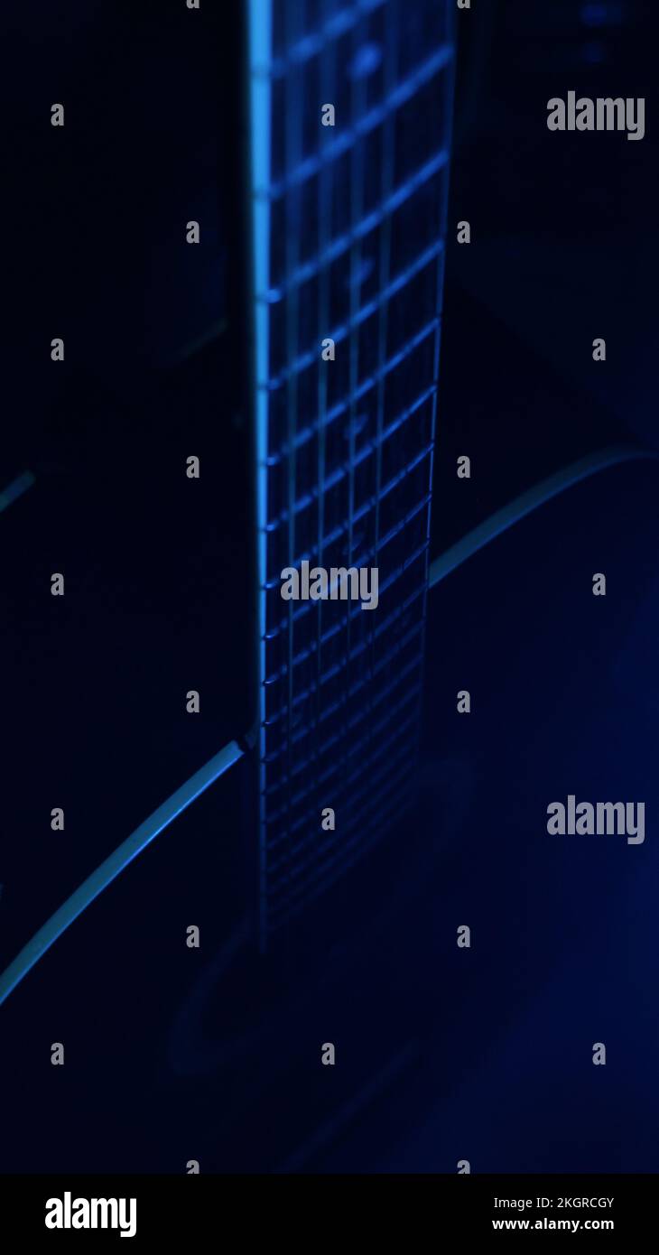 A vertical image of electric guitar strings in blue neon light in the ...