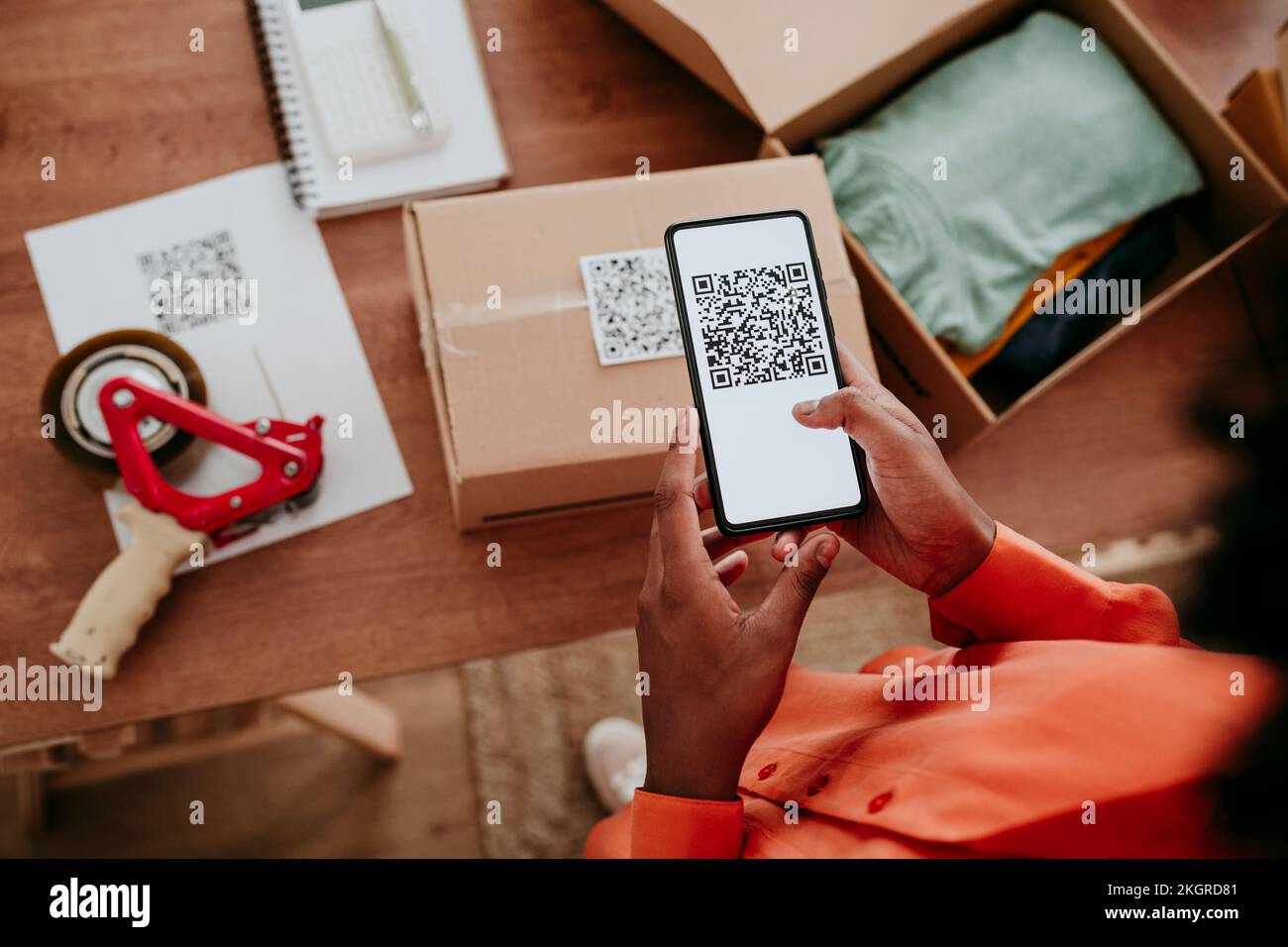 Hands of businesswoman scanning QR code through smart phone on package ...