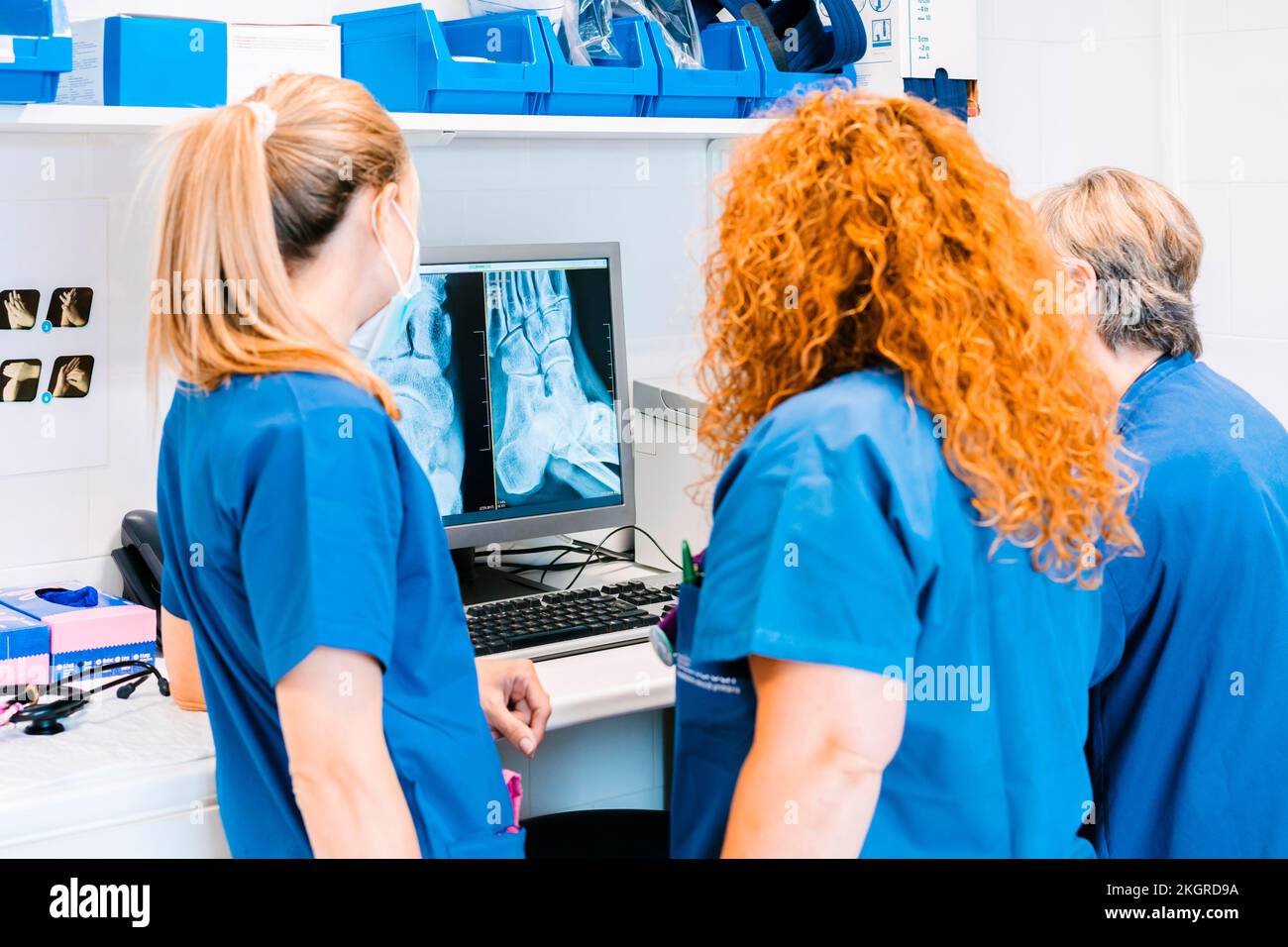 Mature nurse with colleagues examining x-ray image on computer at ...