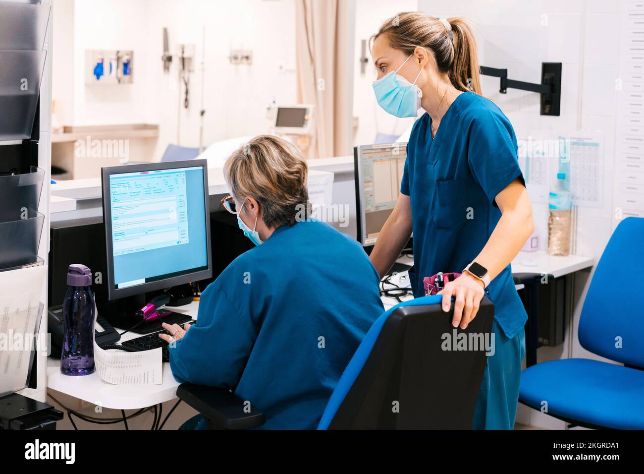 Mature nurse with colleague discussing over computer at hospital Stock ...