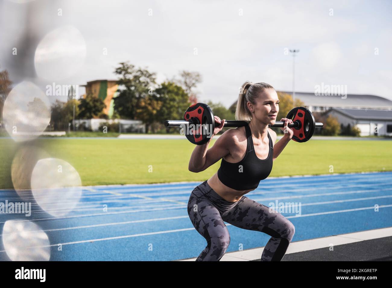 Young athlete exercising with barbell by running track Stock Photo - Alamy