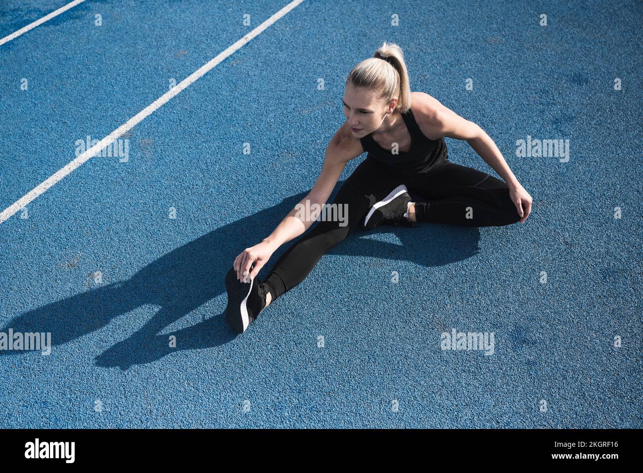 Young athlete doing warm up exercise on track Stock Photo - Alamy