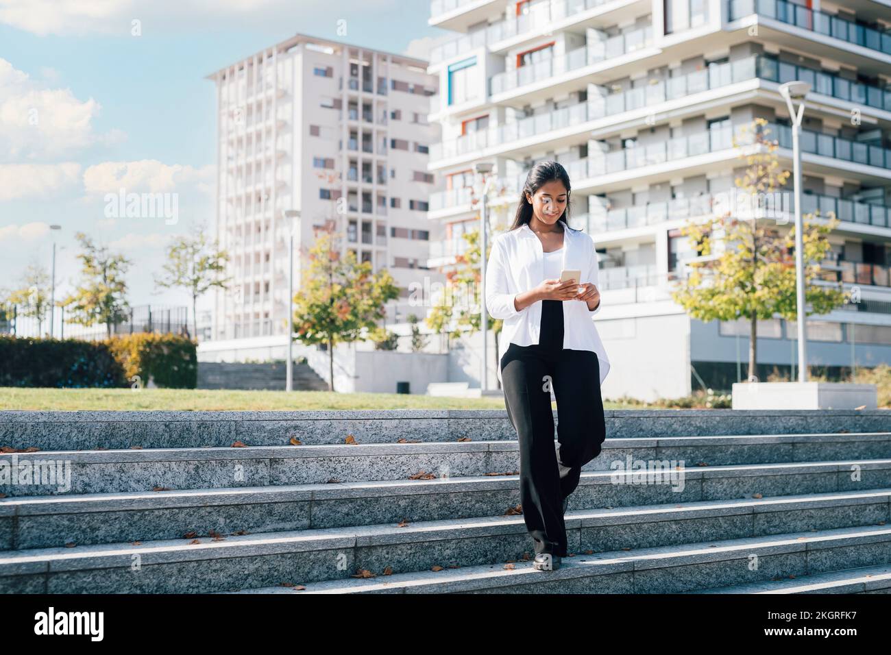 Young woman using smart phone and walking on steps Stock Photo - Alamy