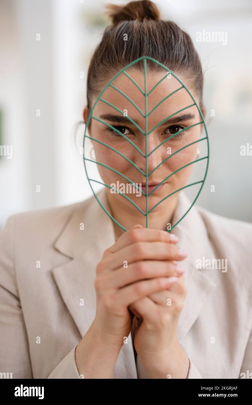 Businesswoman looking through leaf shape model in office Stock Photo ...